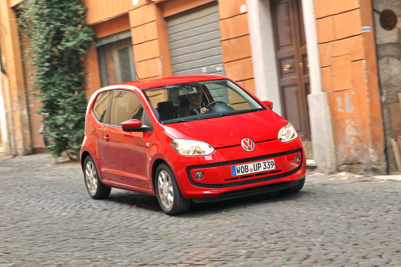 Photo 14 - Volkswagen up rouge roulant le long d'une façade coorée vue ...